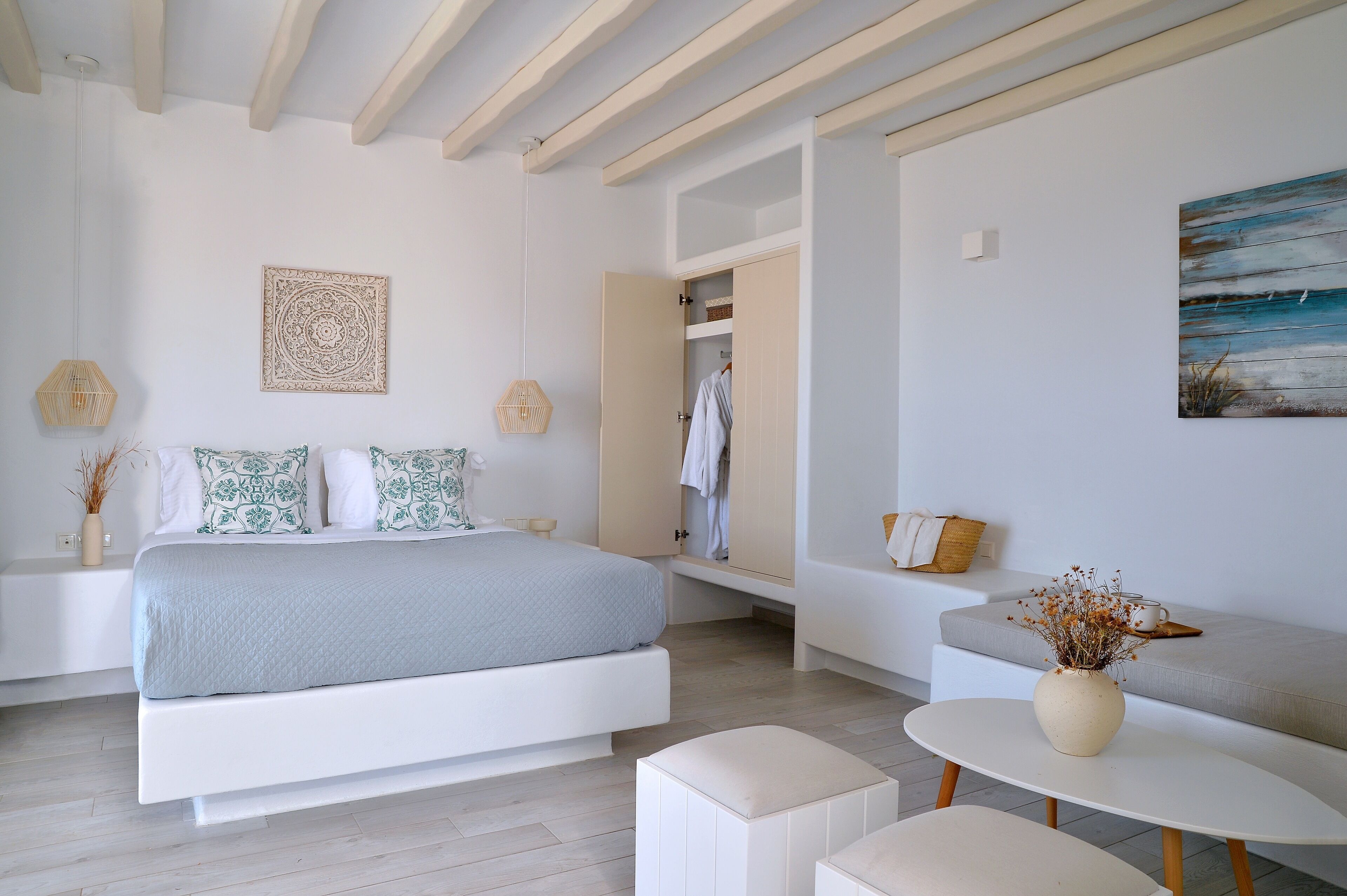 Quarto moderno com uma cama grande, mesa de cabeceira, mesinha redonda e um sofá.