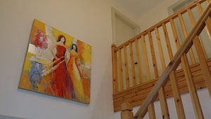 Uma escadaria com guarda-corpos de madeira e um quadro na parede.