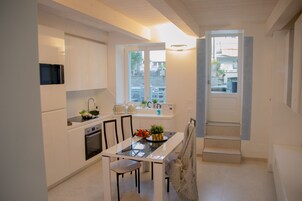 Uma cozinha moderna com armários brancos, uma mesa de jantar com cadeiras, forno embutido e janela com vista para o exterior.