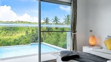Quarto com uma grande janela com vista para uma piscina e vegetação exuberante.