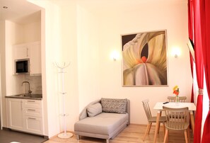 Um espaço compacto com cozinha compacta, sofá, mesa de jantar com cadeiras e um quadro na parede.