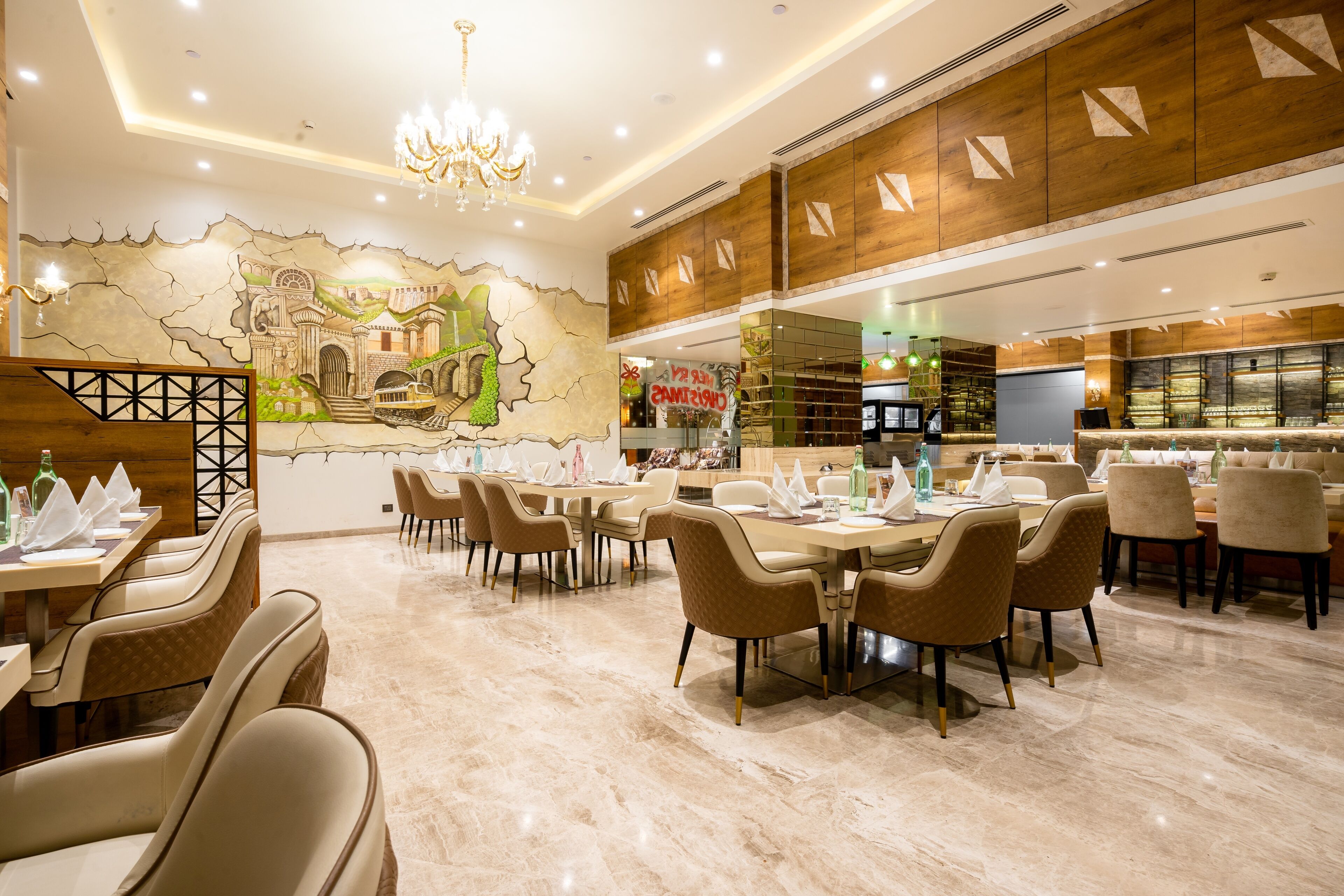 Restaurante com piso de mármore, paredes revestidas de madeira e um mural representando uma paisagem. As mesas estão dispostas com cadeiras e guardanapos.