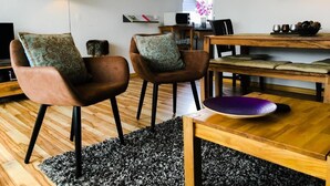 Uma sala de estar moderna com duas poltronas de couro, uma mesa de centro de madeira e uma mesa de jantar com cadeiras.