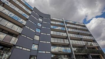 Um edifício moderno com fachada curva, várias janelas e antena visível.