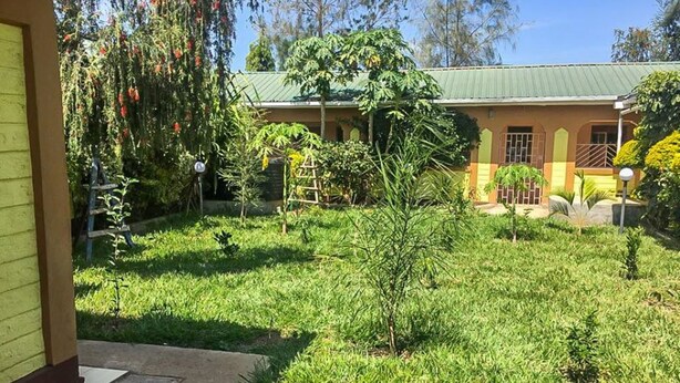 Um edifício com telhado verde e um jardim bem cuidado, com diversas plantas e uma pequena árvore.