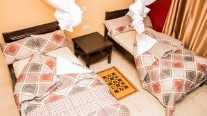 Quarto com duas camas, cada uma com dossel, uma mesinha e um tapete estampado.