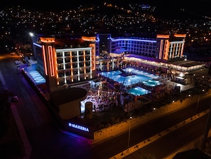 Um hotel com uma ampla área de piscina externa, várias varandas e um letreiro chamativo 'MAXERIA'.