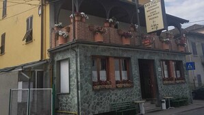 Um edifício de dois andares com fachada amarela e base de pedra. Possui uma placa com a inscrição 'Bar Italia', indicando que se trata de um restaurante.