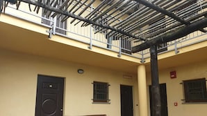 Um edifício com fachada amarela, um banco de madeira e um guarda-corpo de metal.