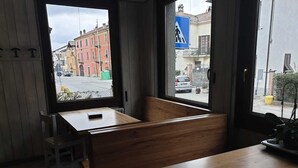 Um restaurante com mobiliário de madeira, grandes janelas e vista para a rua.