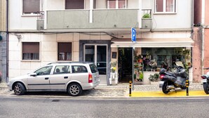 Um edifício com placa de estacionamento, um carro estacionado e uma motocicleta.
