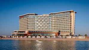 Um hotel grande com vários andares, fachada curva e localização à beira-mar.