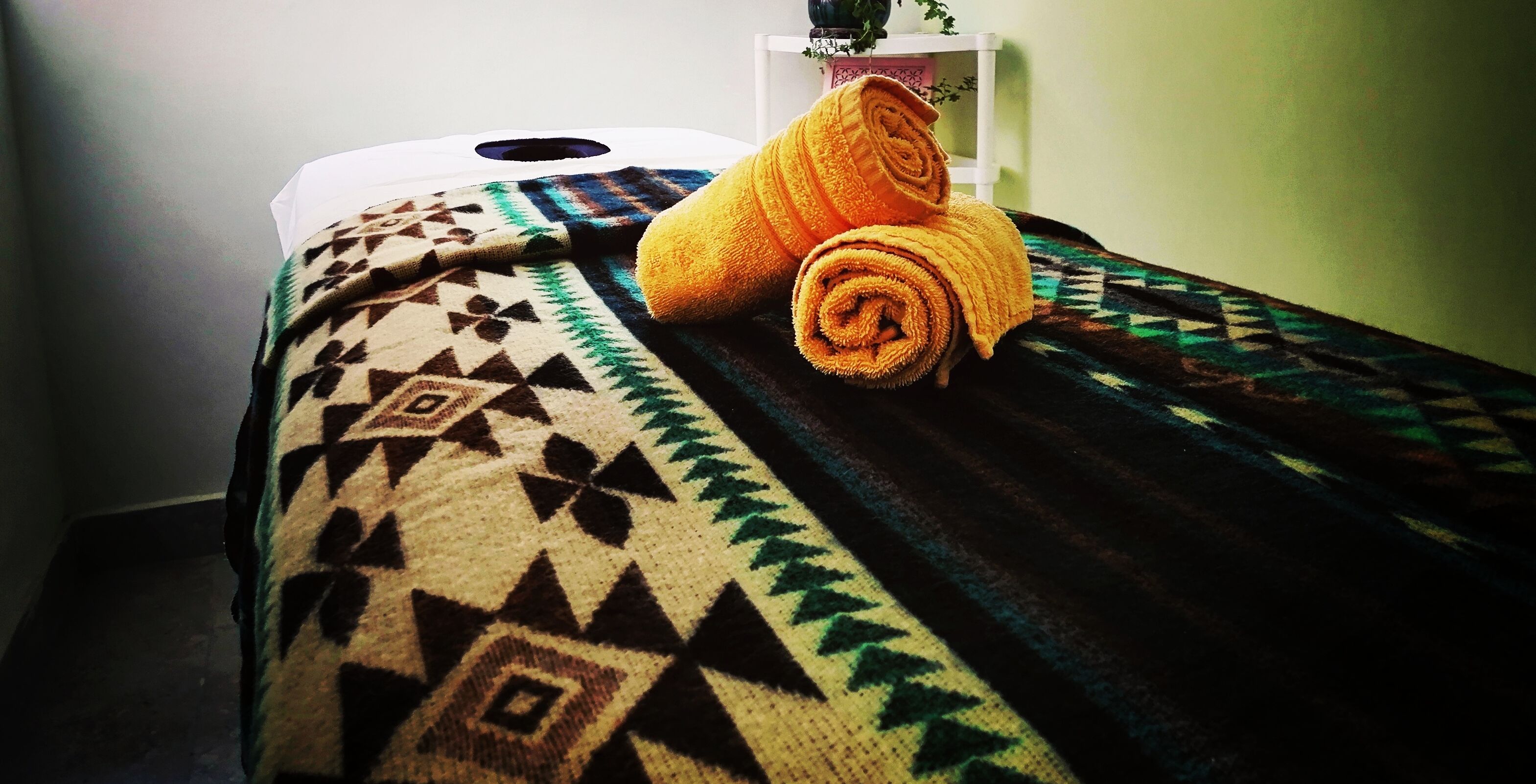 Uma cama com um cobertor estampado e duas toalhas enroladas.