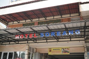 Um hotel chamado 'HOTEL SOREANG' com uma placa, entrada coberta e um banner de aviso.