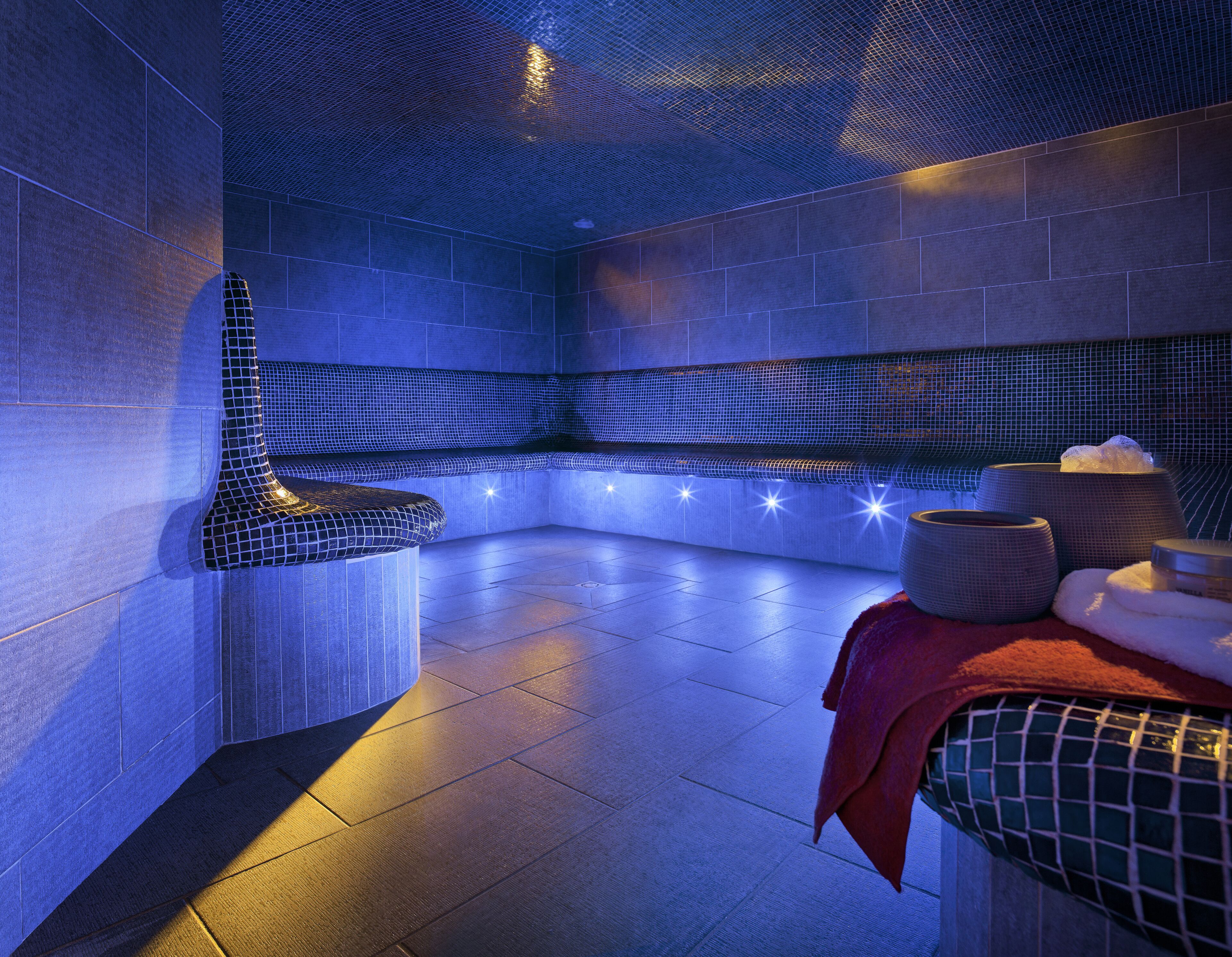 Um spa moderno com um banco curvo, uma pequena mesa com toalhas e piso de azulejos.