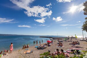 Na praia, areia branca, espreguiçadeiras, guarda-sóis 