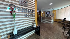Uma área de recepção com uma placa indicando "DOMUS HOTEL" e um balcão de atendimento.