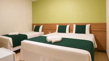 Quarto de hotel com duas camas, cabeceira de madeira e parede verde.