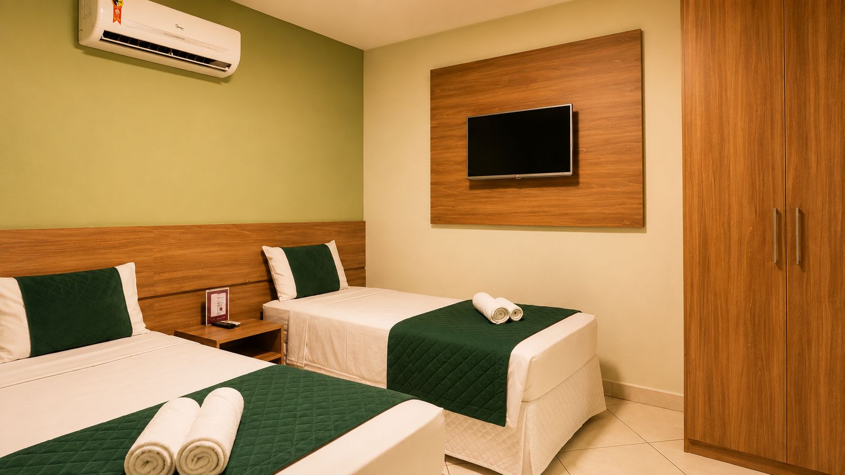 Quarto de hotel com duas camas, uma televisão na parede e um guarda-roupa.