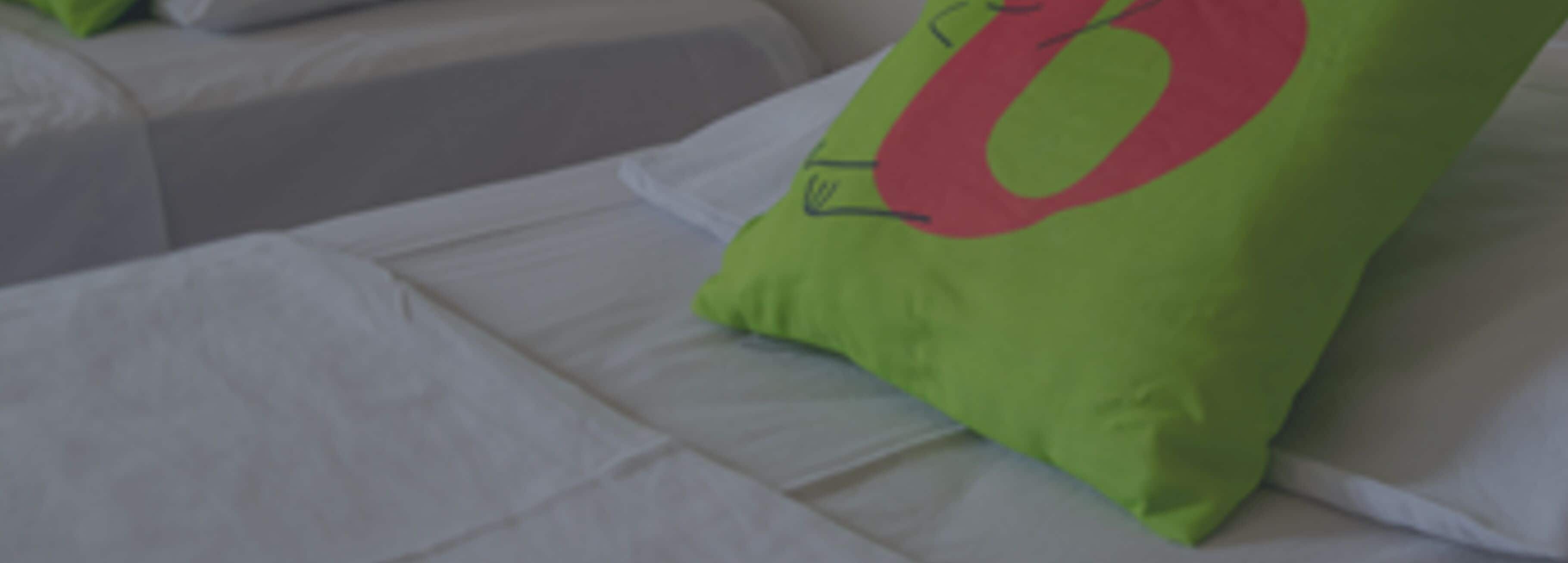 Uma cama com travesseiro verde e um desenho vermelho.