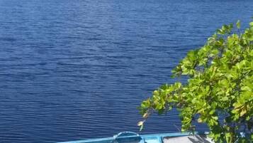 Um barco atracado em um lago calmo, com margem gramada e um edifício ao fundo.