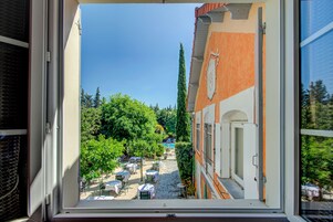Vista da janela sobre um pátio com área de estar externa e piscina.