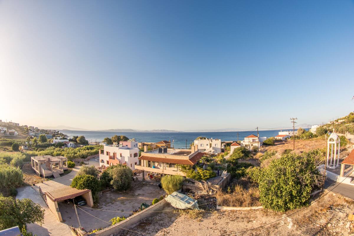 Uma vila costeira com edifícios, céu claro e vista para o mar.