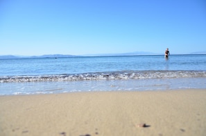 Uma praia com água azul cristalina e uma pessoa em distância.
