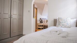 Quarto com uma cama grande, um guarda-roupa e uma porta arqueada para um banheiro.