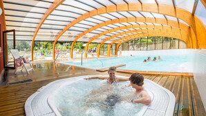 Área de hidromassagem com deck de madeira e piscina ao fundo.