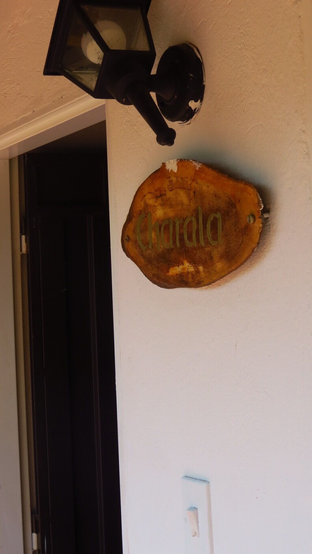 Uma placa de madeira com o nome 'Charola' numa parede.