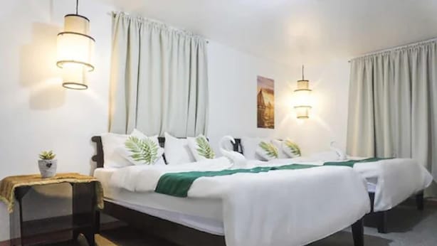 Quarto de hotel com uma cama de casal, duas mesas de cabeceira e duas luminárias fixadas na parede.