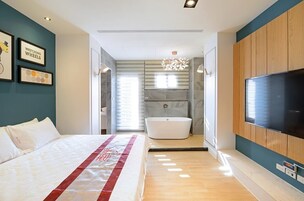 Quarto de hotel moderno com uma cama grande, televisão de tela plana, banheira e vista para a cidade.