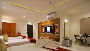 Quarto de hotel com duas camas, televisão, escrivaninha e uma cadeira.