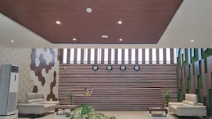Um hall moderno com teto de madeira, balcão de recepção e área de estar com sofás.
