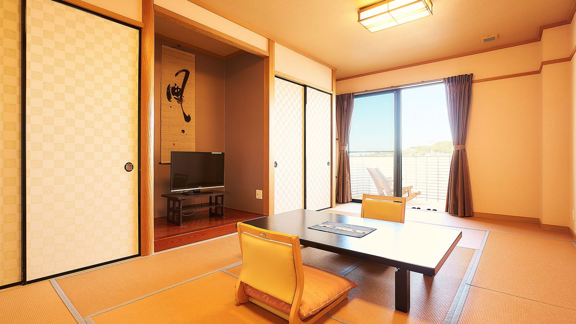 Um quarto tradicional em estilo japonês, com piso de tatame, televisão sobre um suporte baixo e uma porta deslizante que d á para uma varanda.