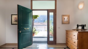 Um quarto com uma porta verde, uma cômoda de madeira e uma máquina de costura.
