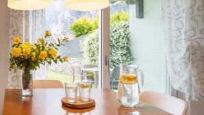 Uma mesa de jantar com um vaso de flores amarelas, dois copos de água e um jarro com uma fatia de limão.