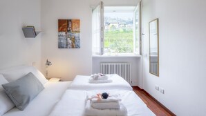 Quarto com duas camas, uma janela com vista, um radiador e um quadro na parede.