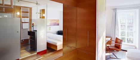 Quarto moderno com guarda-roupa espaçoso, cama, escrivaninha e vista para o exterior.