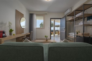 Quarto moderno e bem iluminado, com uma cama grande, uma escrivaninha com computador, um espelho e um guarda-roupa.