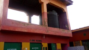Um edifício com uma placa indicando 'CLOAK ROOMS' e uma placa visível de 'BATHROOM'.
