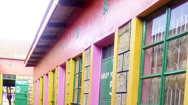 Um edifício com uma fileira de portas e janelas, cada uma com cor diferente.