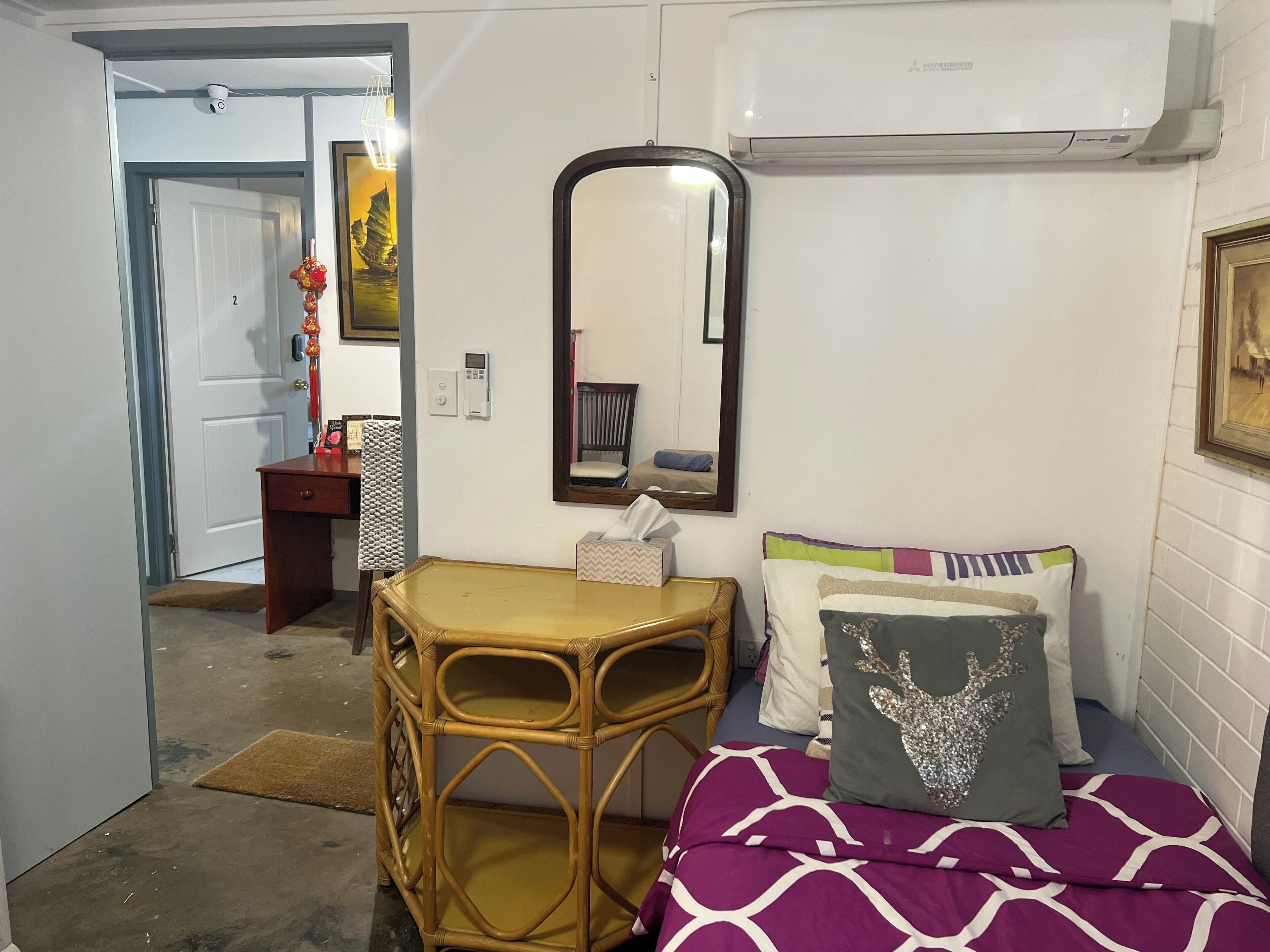 Quarto com cama, mesa de cabeceira, espelho e ar condicionado.