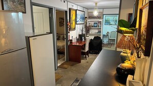Uma cozinha compacta com geladeira, uma mesa de jantar com cadeiras e um pequeno espaço para escritório.