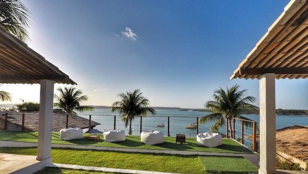 Vista de uma área à beira-mar com um gazebo, mobiliário ao ar livre e uma visão ampla do mar.