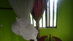 Um quarto com uma cama, uma janela com grades e uma cortina.