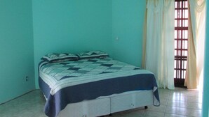 Quarto com cama, janela com cortinas e piso de azulejos.