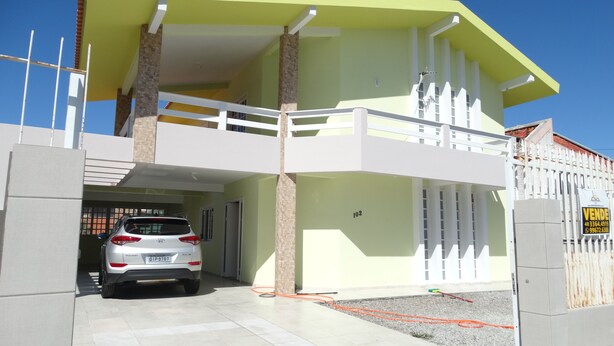 Um edifício de dois andares com um carro estacionado na entrada.