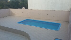 Piscina retangular com borda azul em um terraço.
